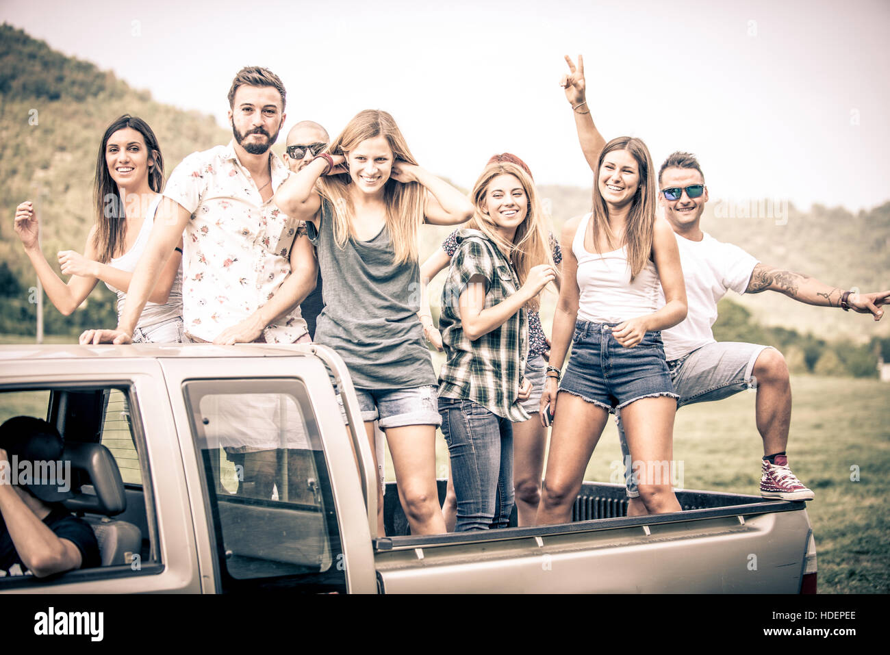 Group of friends driving on the back of pick-up car and having fun ...