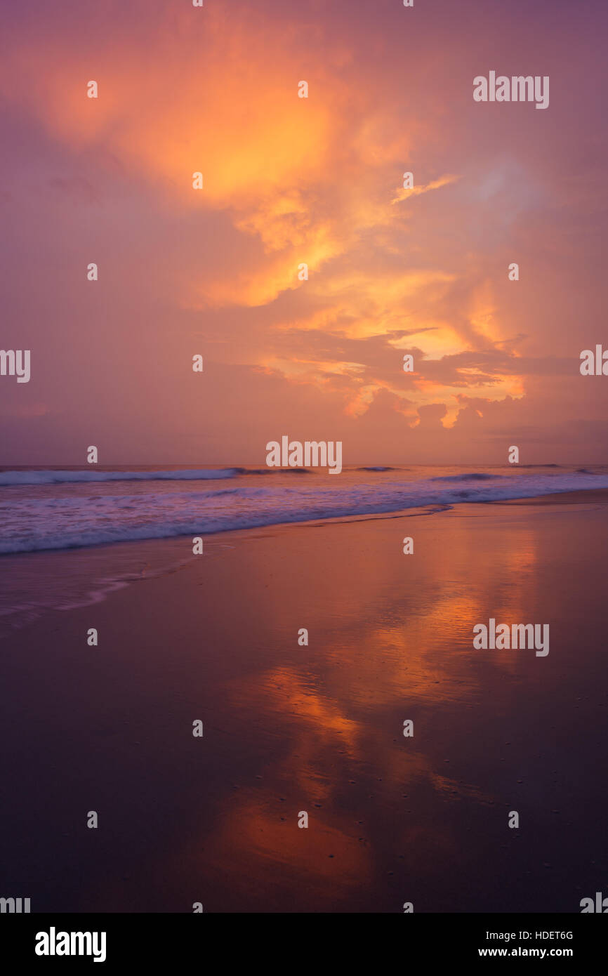 Sunset clouds and waves on empty beach Stock Photo - Alamy