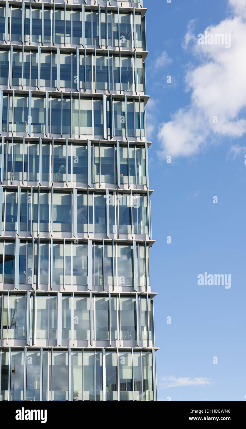Side of a vertical glass office skyscraper with empty blue sky on the ...