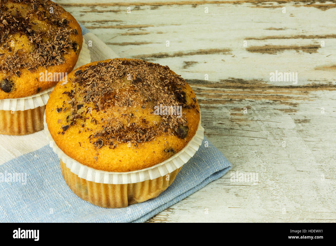 Two sponge muffins sprinkled with grated black chocolate on old wooden ...