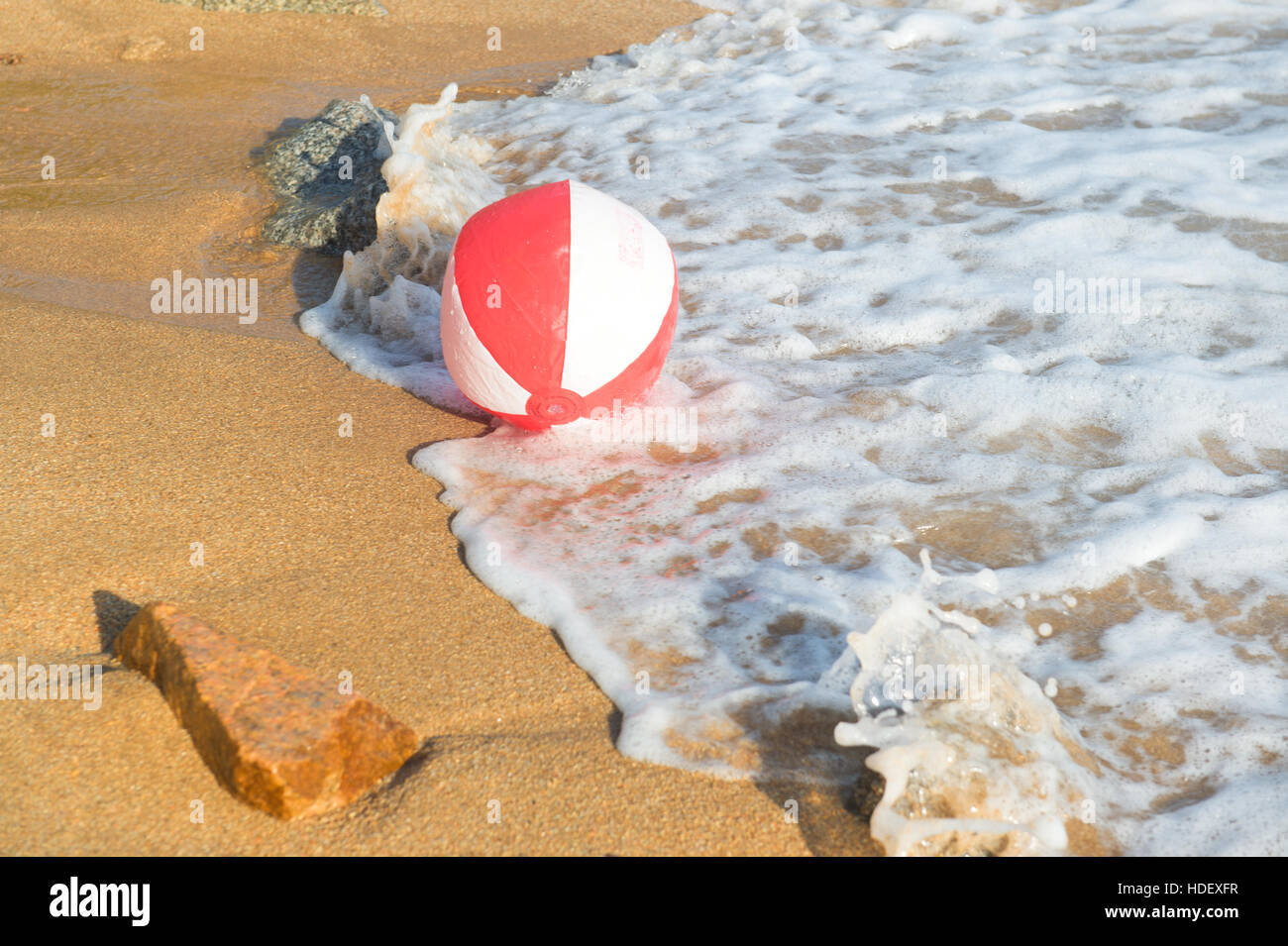 Red and white beach ball playing with the surf and the sea at the beach ...