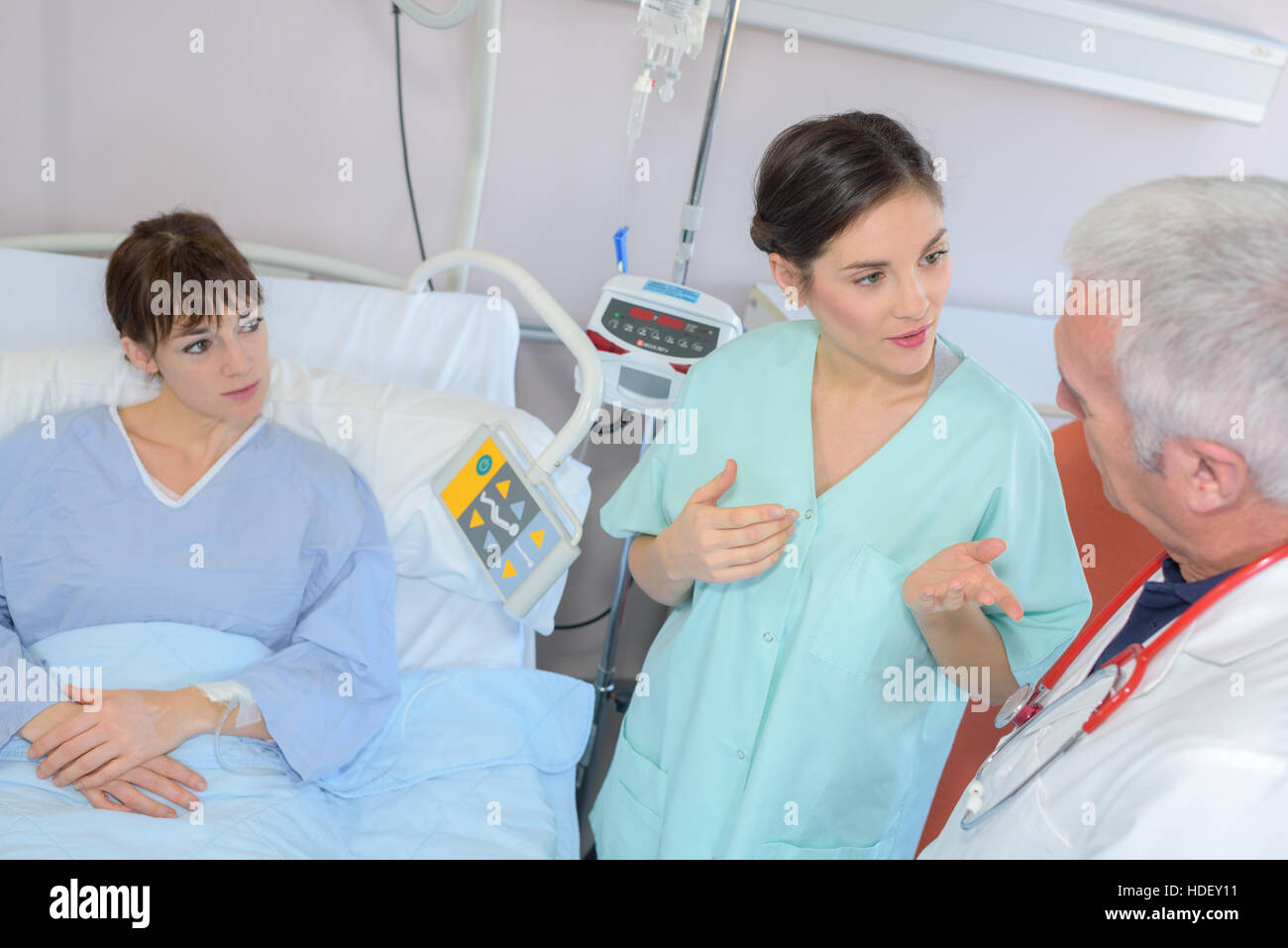 Patient in hospital bed, medical staff in discussion Stock Photo - Alamy