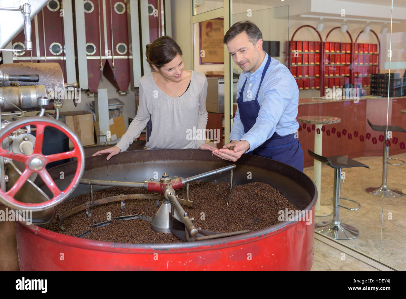 Man and woman looking into vat of coffee beans Stock Photo - Alamy