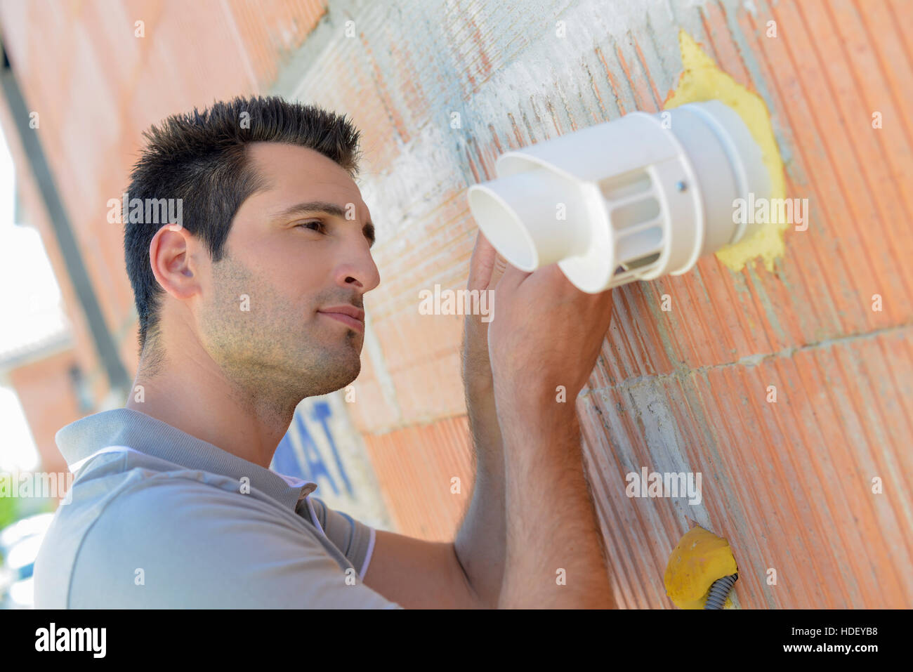 Man fixing vent to exterior wall Stock Photo - Alamy