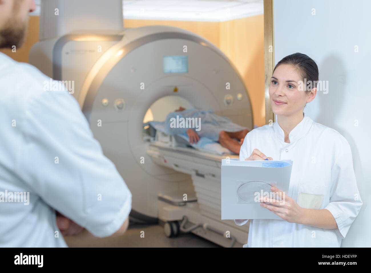 Nurse with file, patient in scanner Stock Photo - Alamy