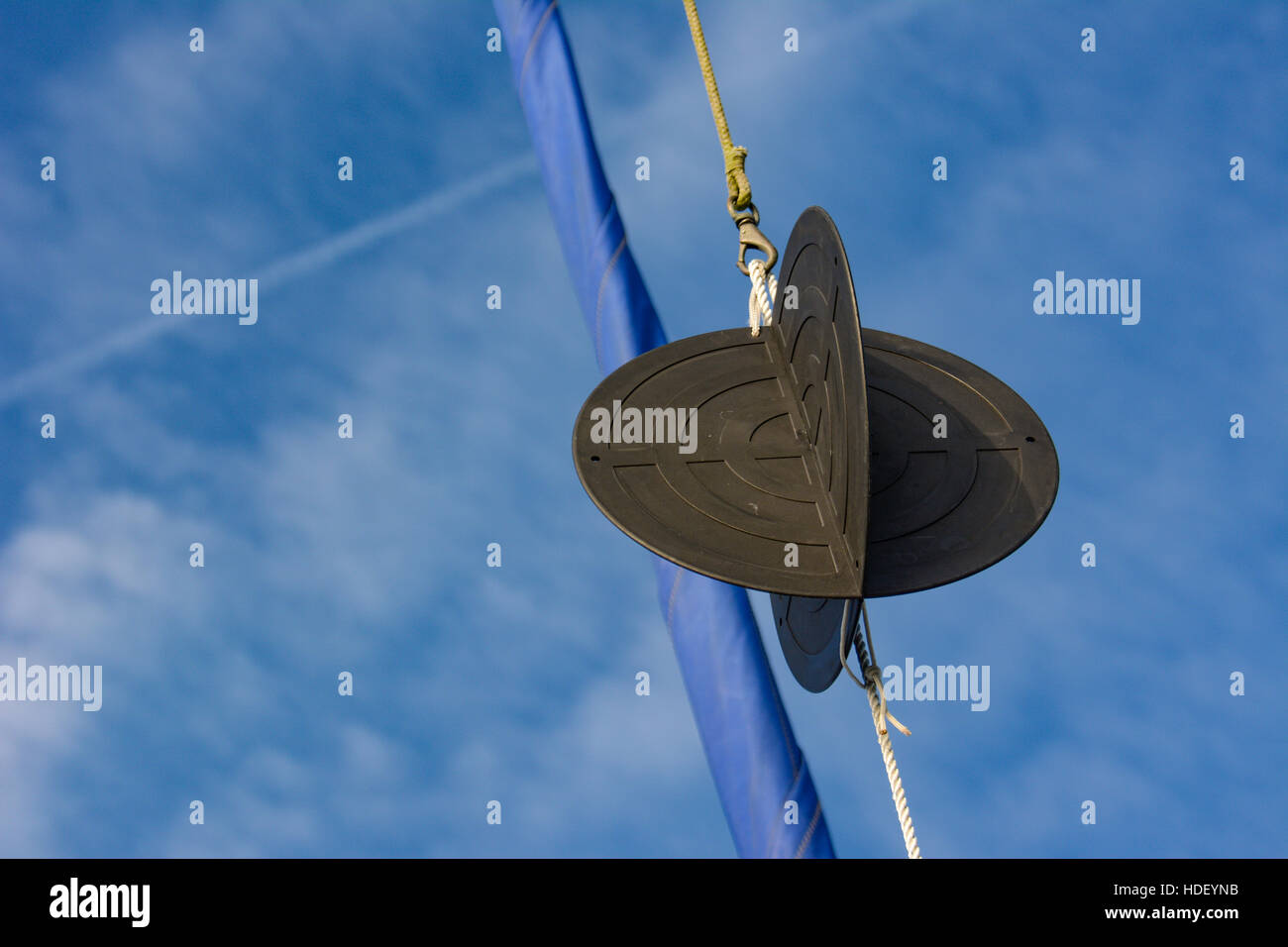 Anchor ball in yachts rigging with rolled blue foresail against a blue ...