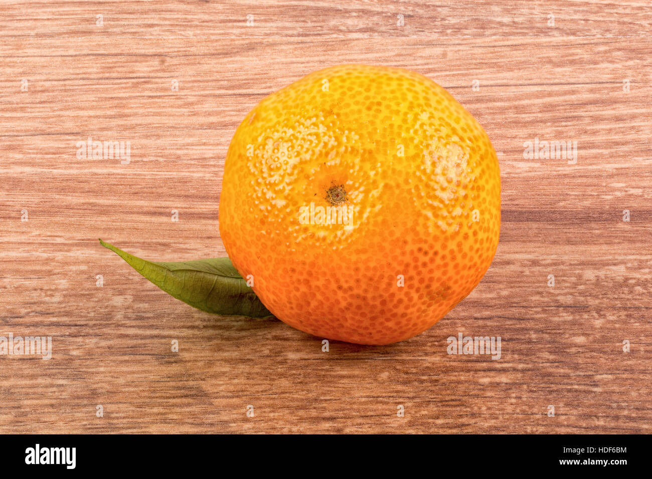 Mandarin with leafs over brown wooden background Stock Photo - Alamy