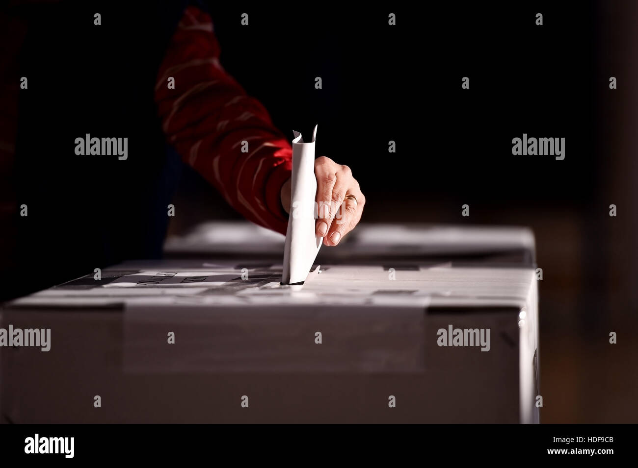 Hand of a person casting a vote into the ballot box during elections ...