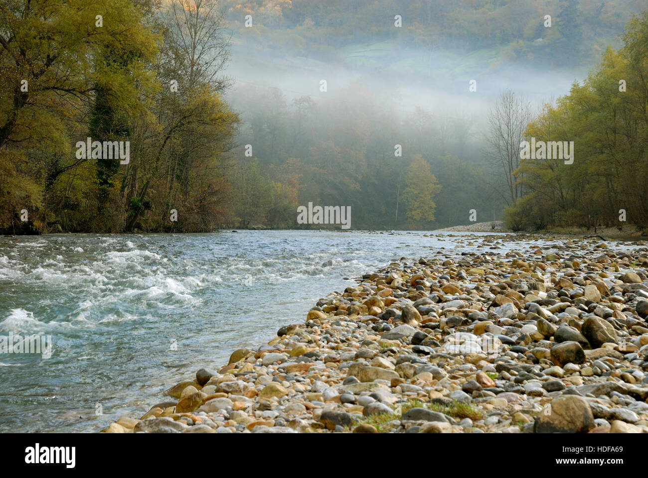River passage through a cobbled area, in the middle of nature, with fog ...