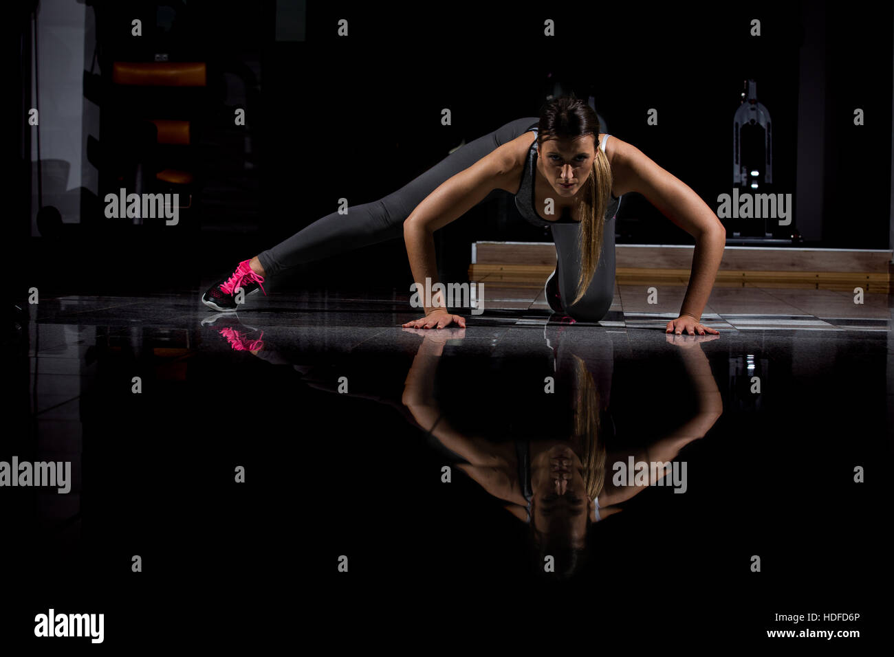 woman in a gym exercising, doing push ups. Dark background Stock Photo ...