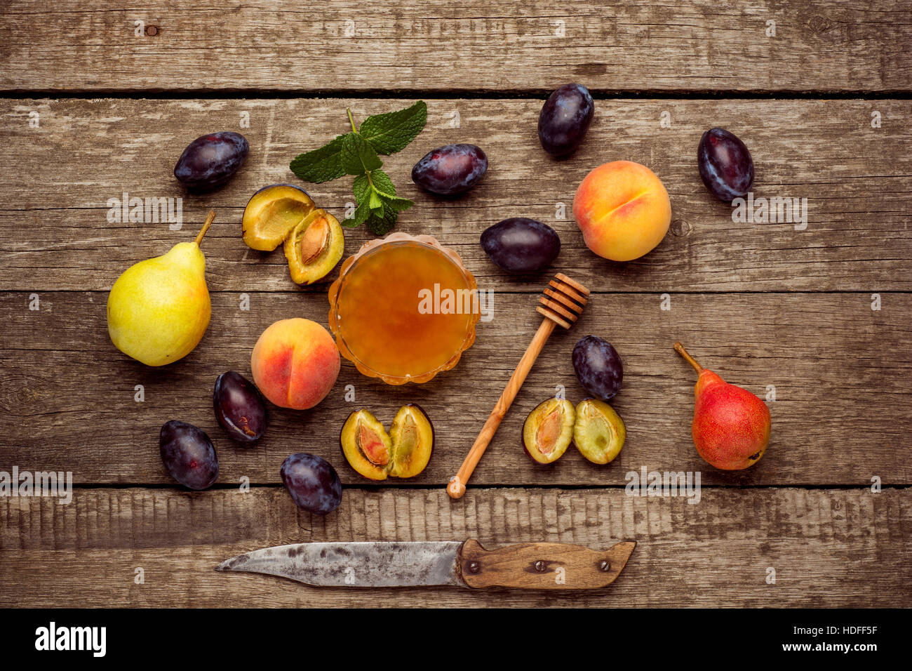 Ripe fruits of peach, plums and pear with honey in a tray on rustic ...