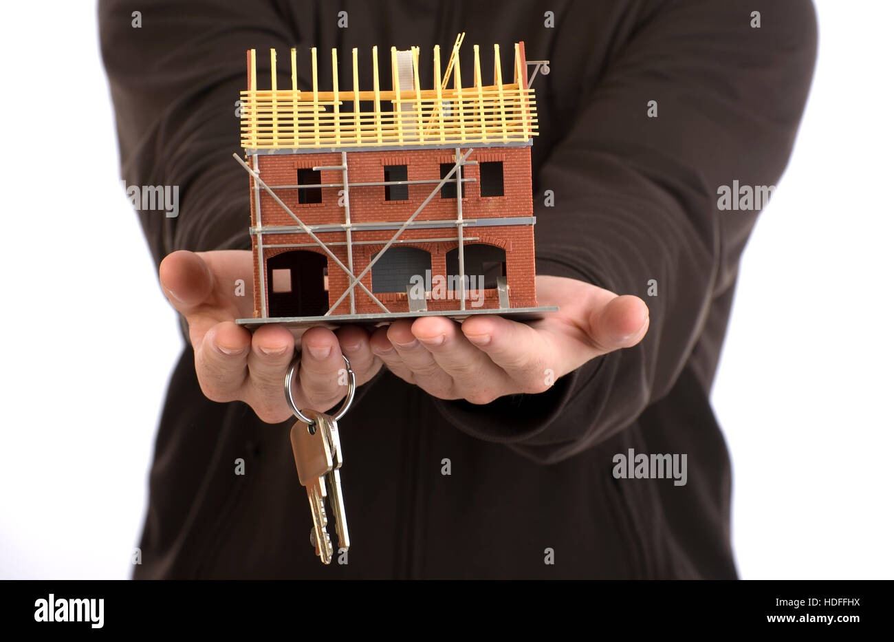 Model of a house under construction and keys held in two hands ...