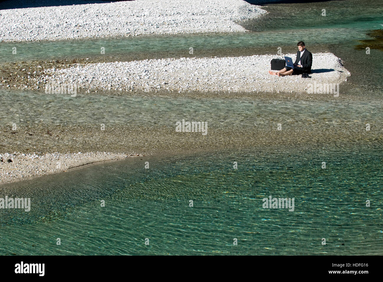Businessman working on his laptop at a river bed Stock Photo - Alamy