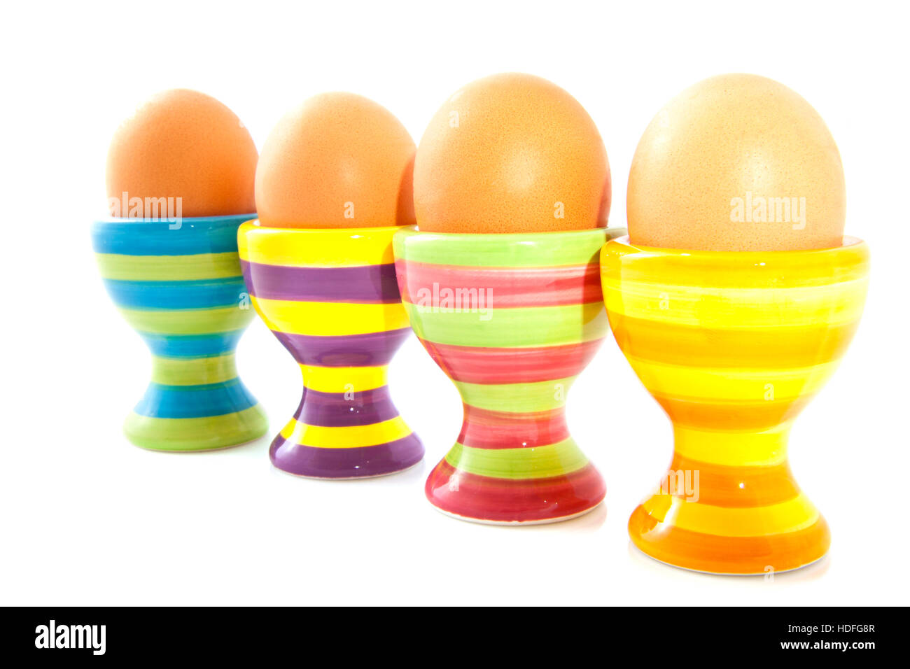 Four colorful striped eggcups in a row isolated over white Stock Photo ...