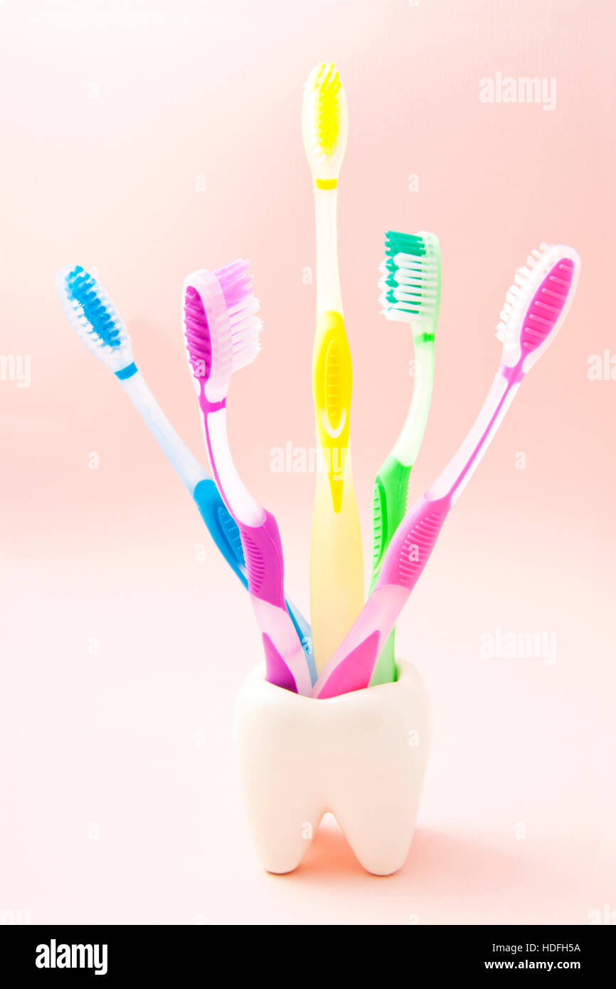 Colorful toothbrushes in a model molar isolated over pink Stock Photo ...