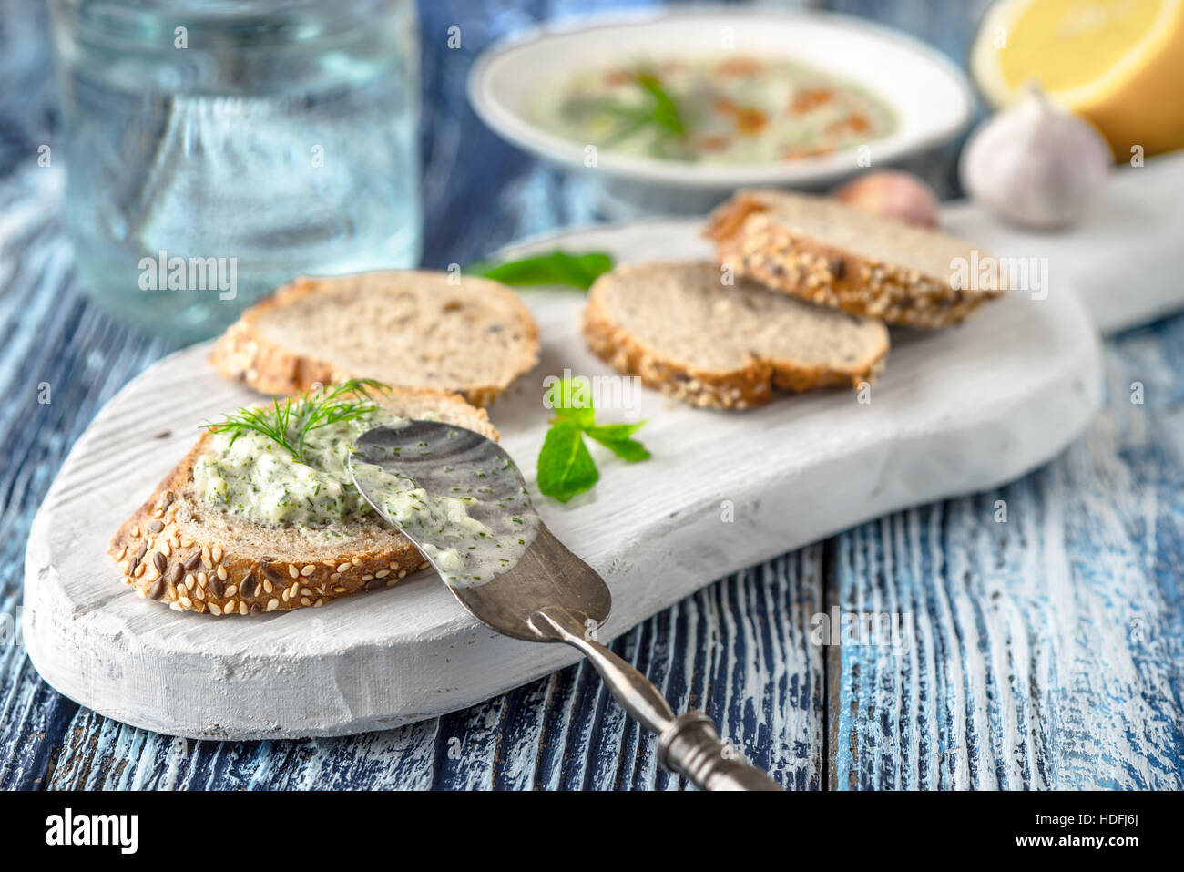 Bread with tzatziki on the white wooden board on the blue table ...