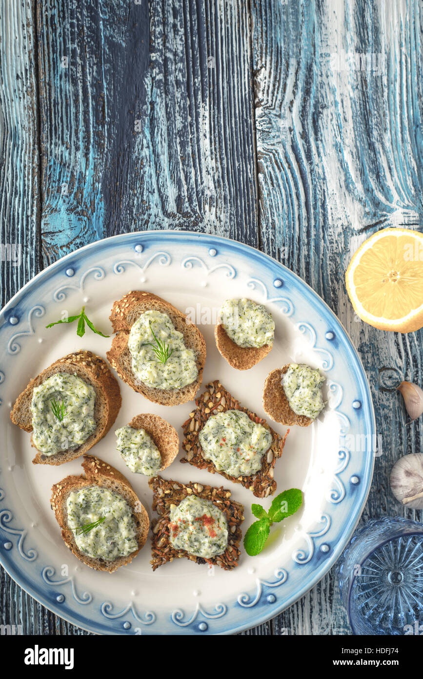 Plate with different bread with tzatziki on the blue wooden table top ...