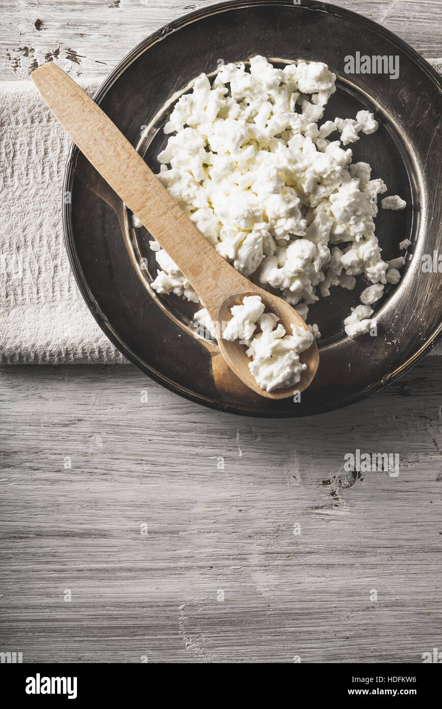 Fresh cottage cheese with wooden spoon on the metal plate on the white ...