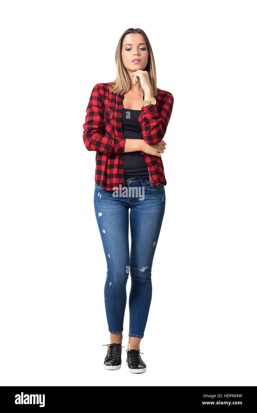 Serious pensive young woman with hands on chin looking down. Full body ...