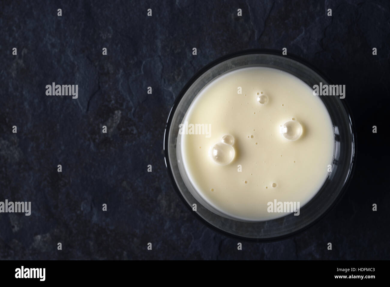 Condensed milk in the glass bowl on the stone background top view Stock ...