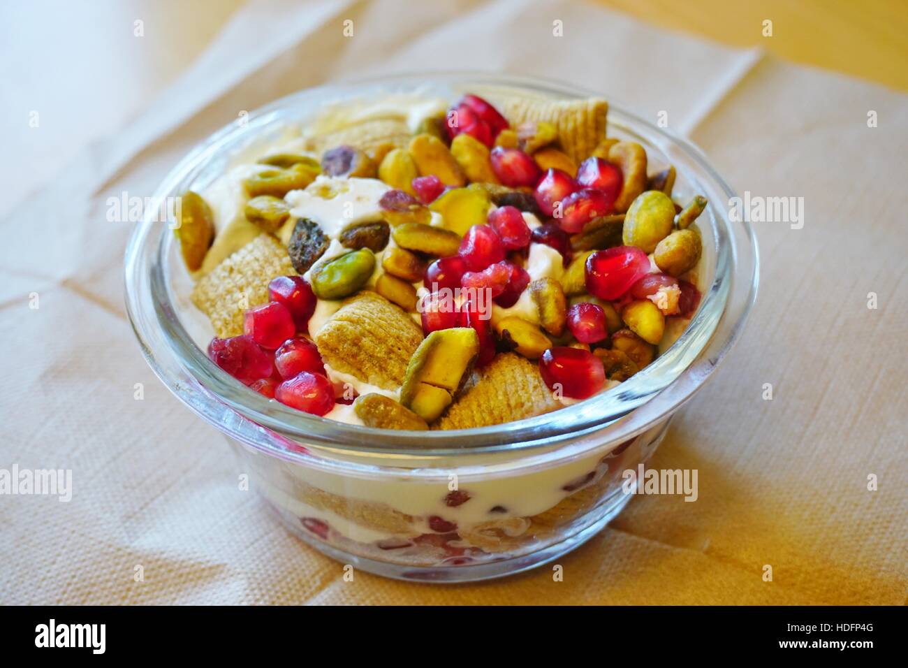 A breakfast yogurt parfait with pomegranates and pistachio nuts in a ...
