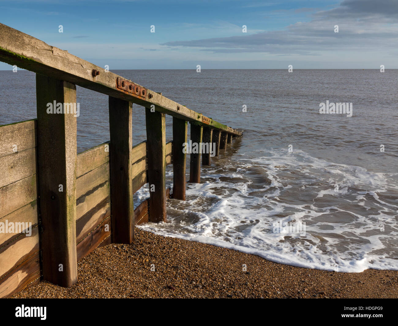 Wooden groynes running from a shingle beach into the sea with horizon ...