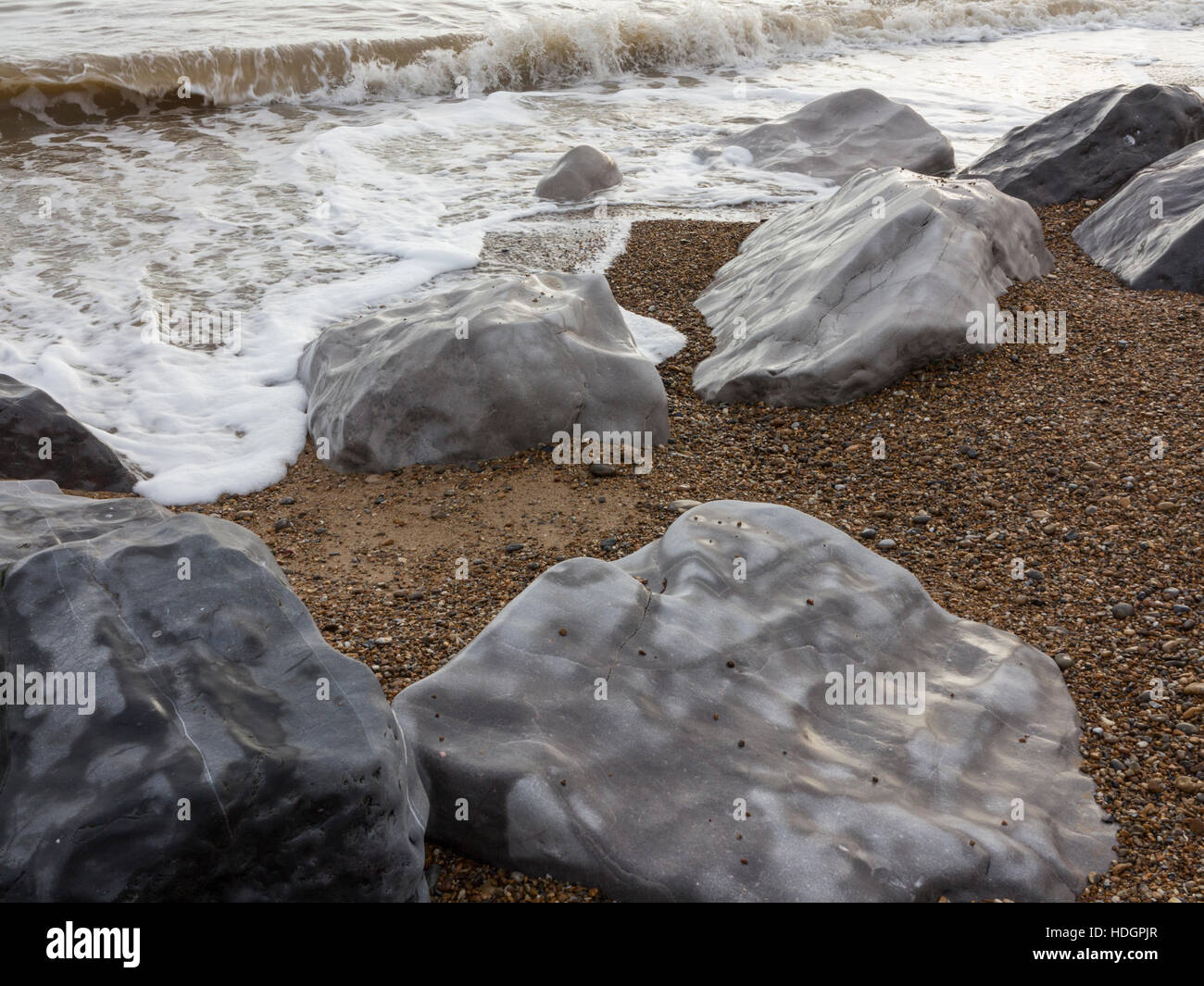 Sea defense boulders on a pebble beach beautifully worn and shaped by ...