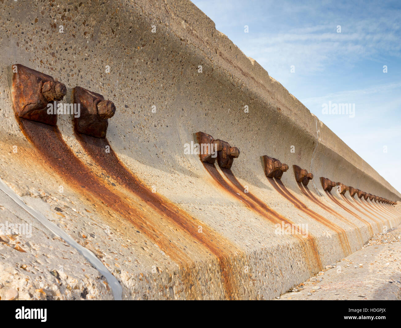 Heavily rust corroded large bolts in a concrete sea wall with oxidation ...