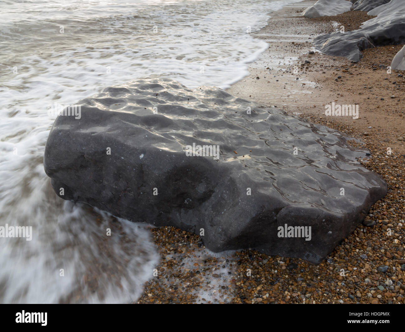 Sea defense boulders on a pebble beach beautifully worn and shaped by ...