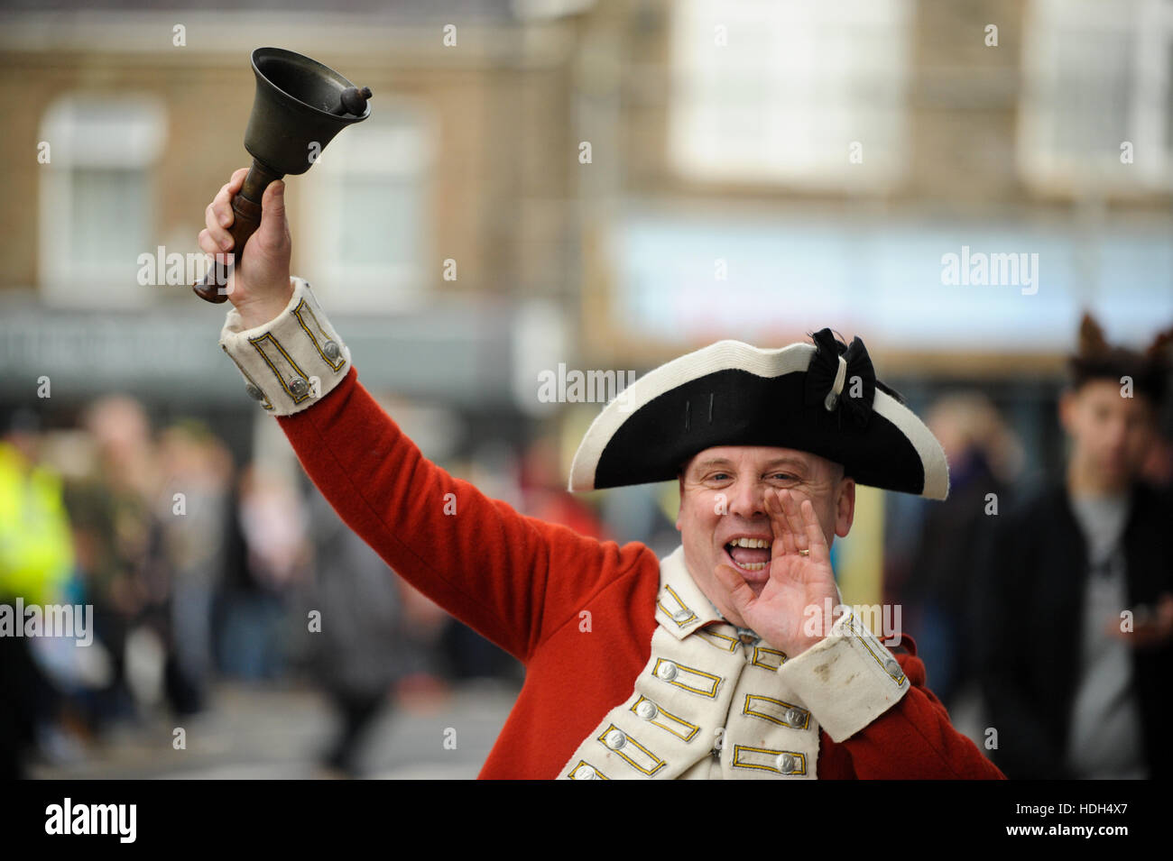 A traditional town crier rings a bell and shouts in a town centre ...