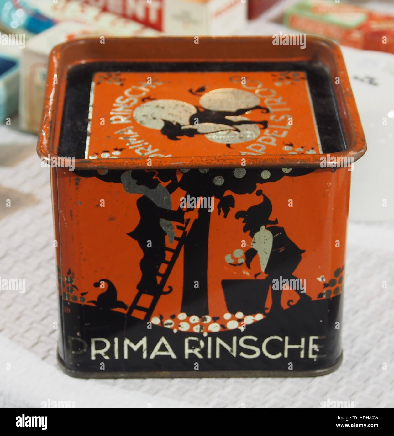 This image depicts a square tin can of Prima Rinsche Appelstroop, a ...