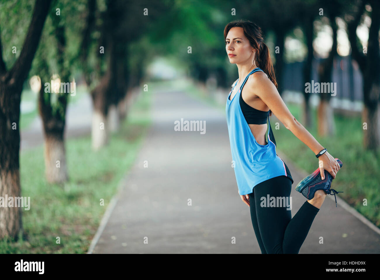 Side view of beautiful woman stretching on footpath at park Stock Photo ...