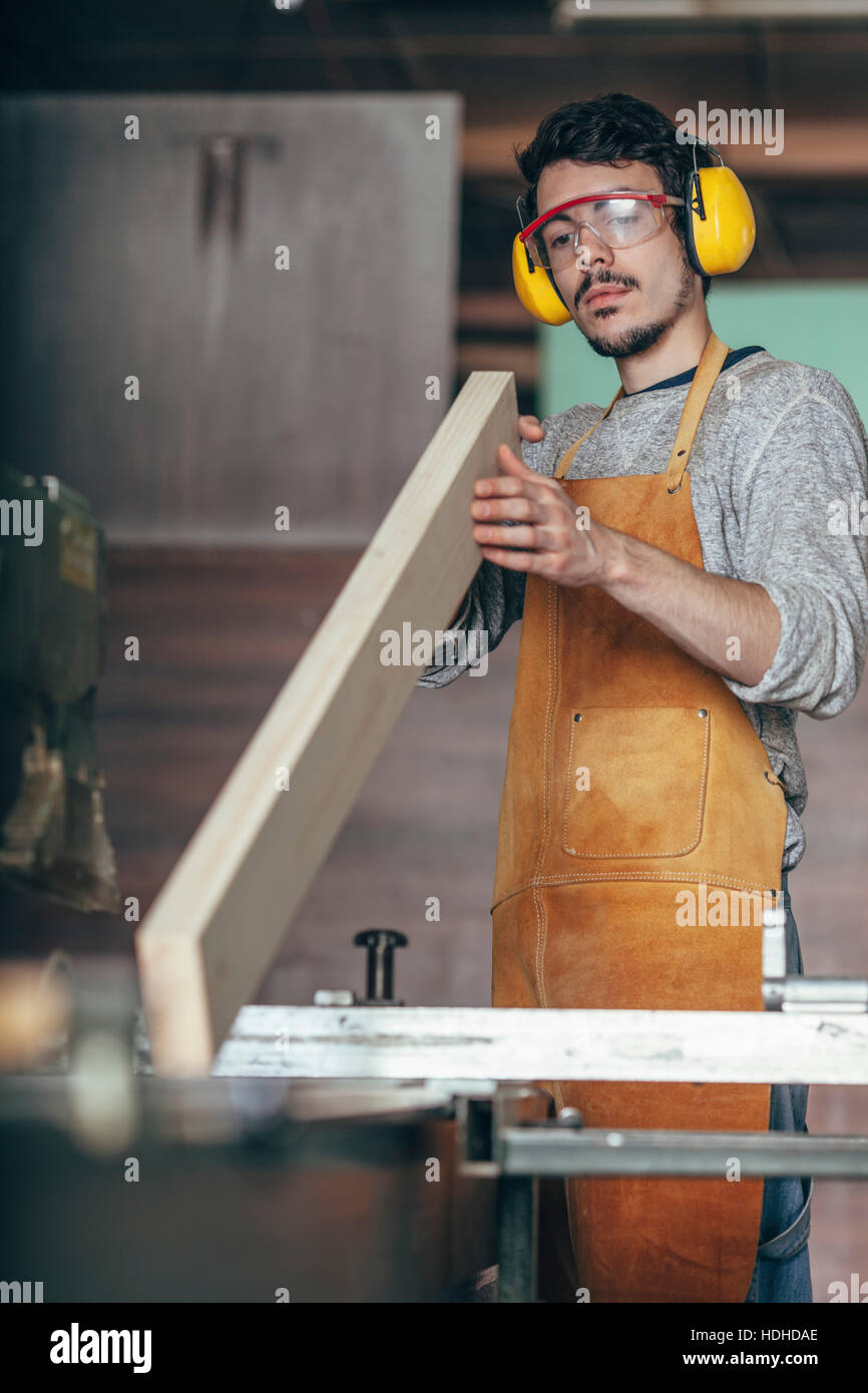 Carpenter examining plank of wood at workshop Stock Photo - Alamy