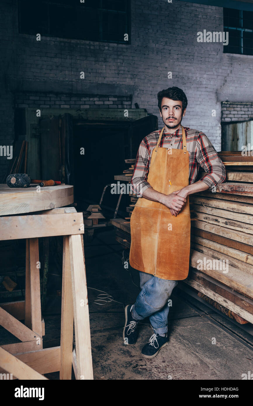 Portrait of carpenter standing by timber stack in workshop Stock Photo ...