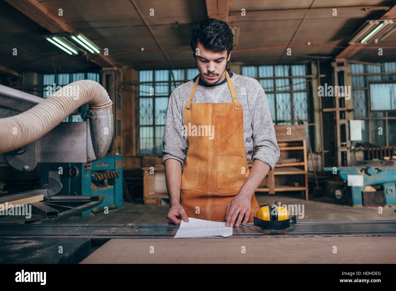 Carpenter reading document on bench in workshop Stock Photo - Alamy