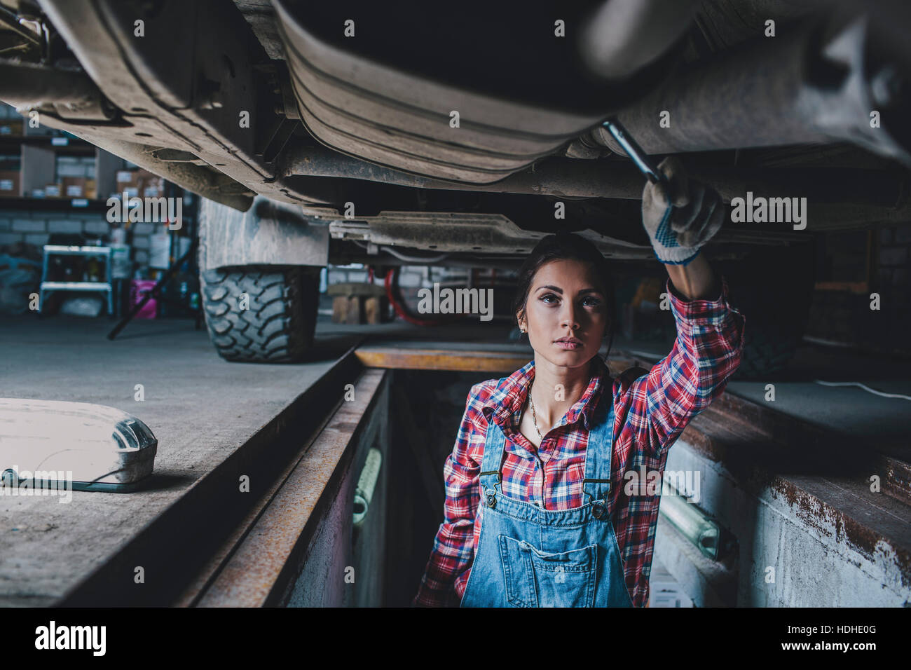 Female mechanic working underneath car at garage Stock Photo - Alamy