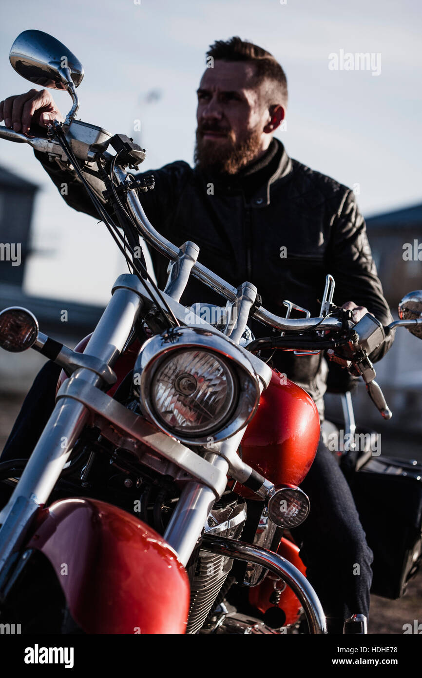 Portrait of biker sitting on motorcycle and looking away Stock Photo ...