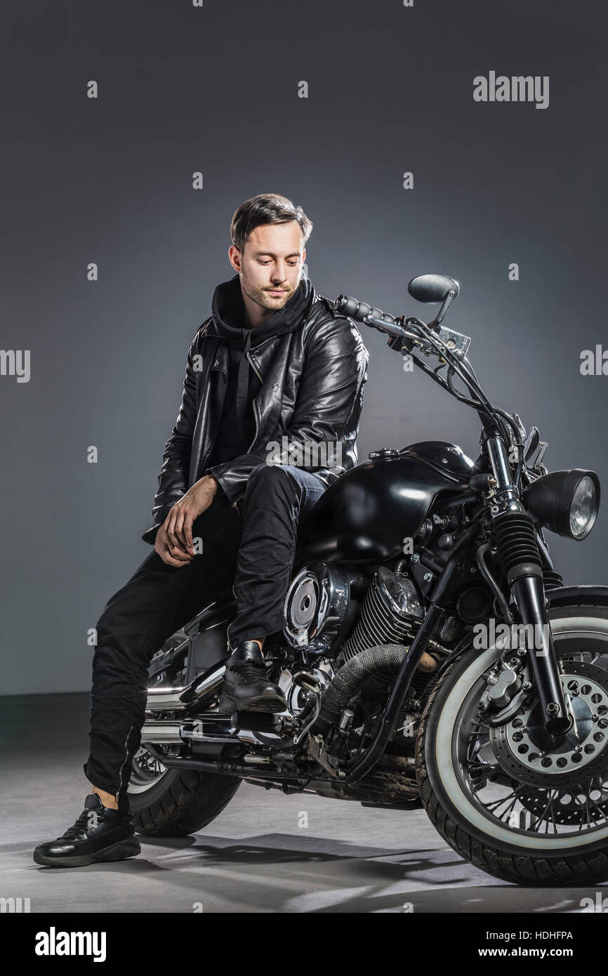 Full length of man sitting on motorcycle against gray background Stock ...