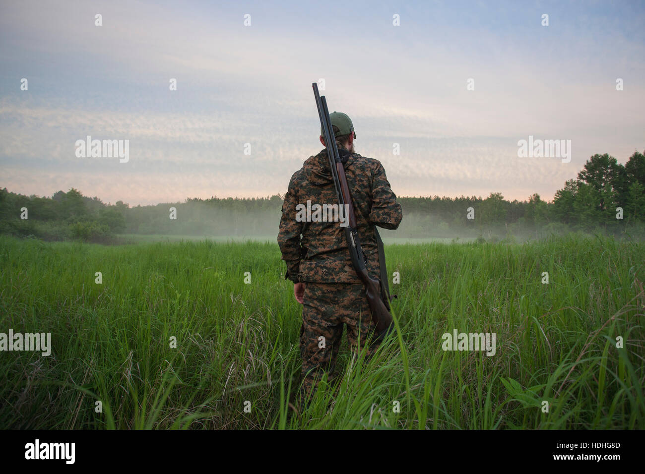 Rear view of hunter standing at grassy field Stock Photo - Alamy