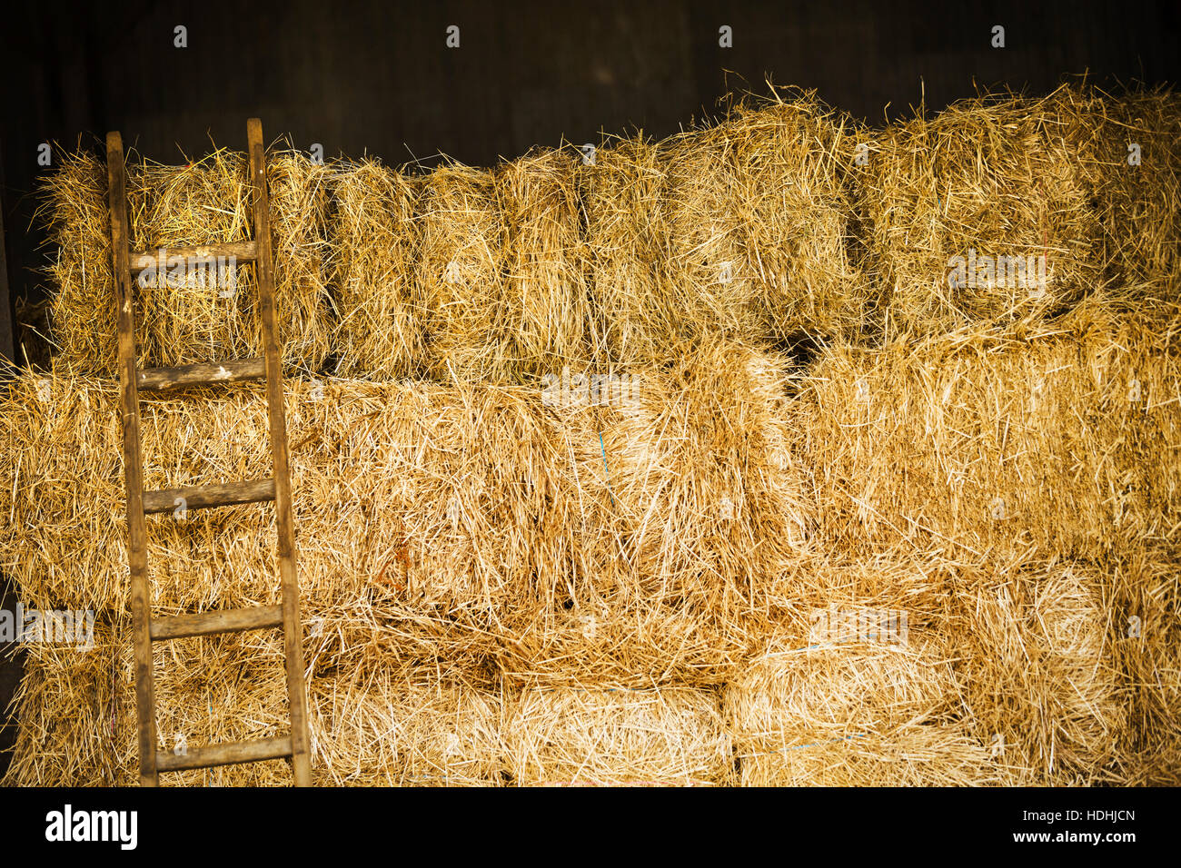 A stack of hay bales with a ladder Stock Photo - Alamy