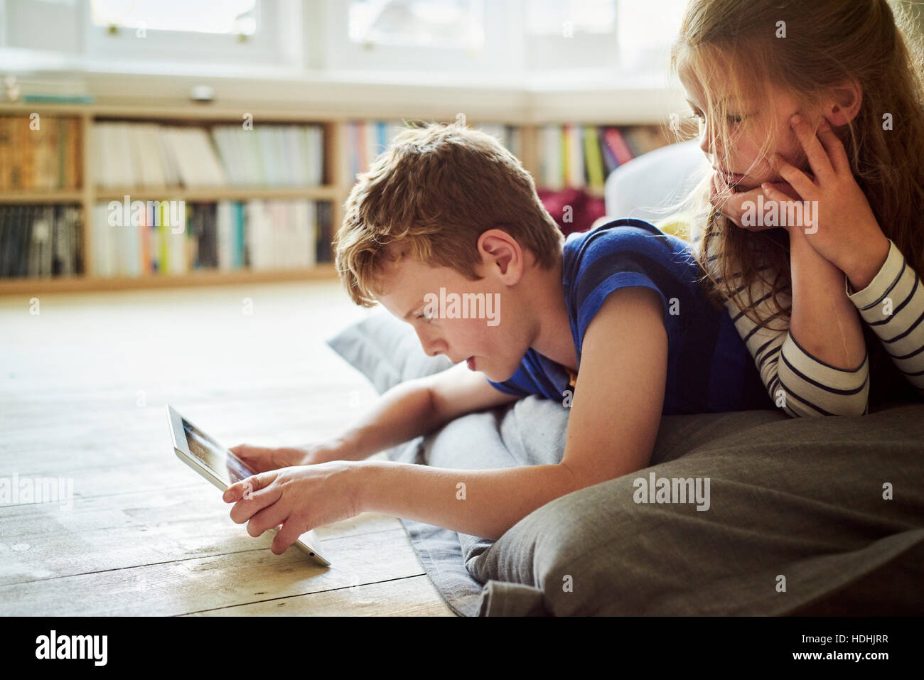 Two children seated sharing a digital tablet watching the screen Stock ...