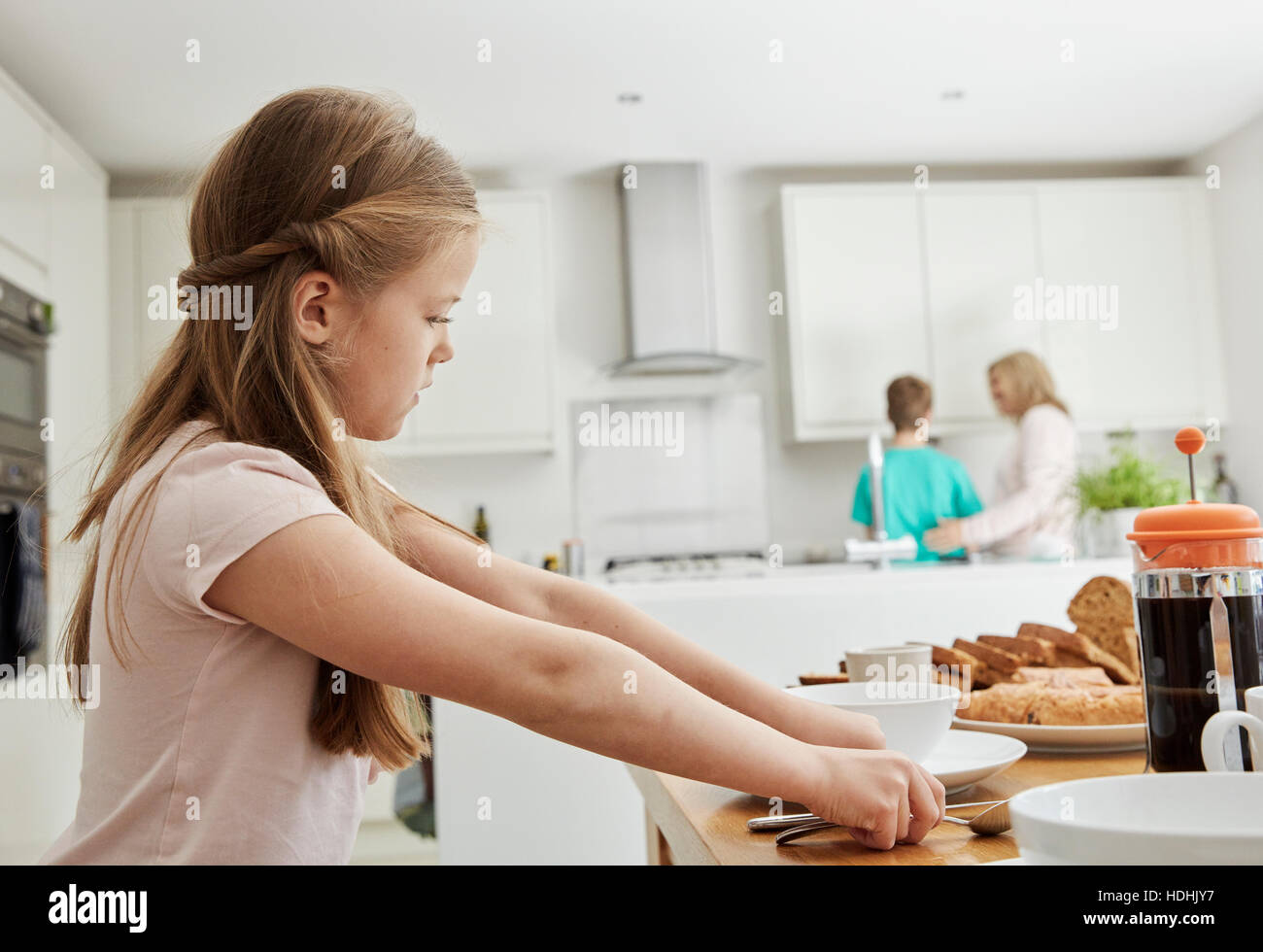 A girl in the kitchen laying the table for breakfast Stock Photo - Alamy