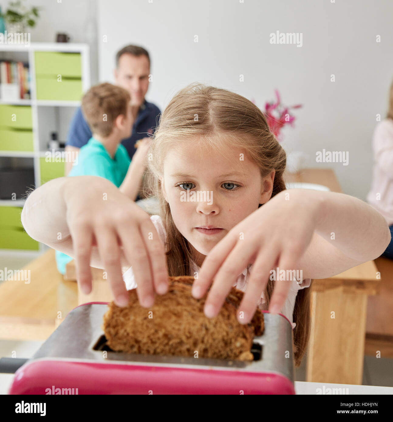 A family making breakfast. A child taking a slice of bread out of the ...