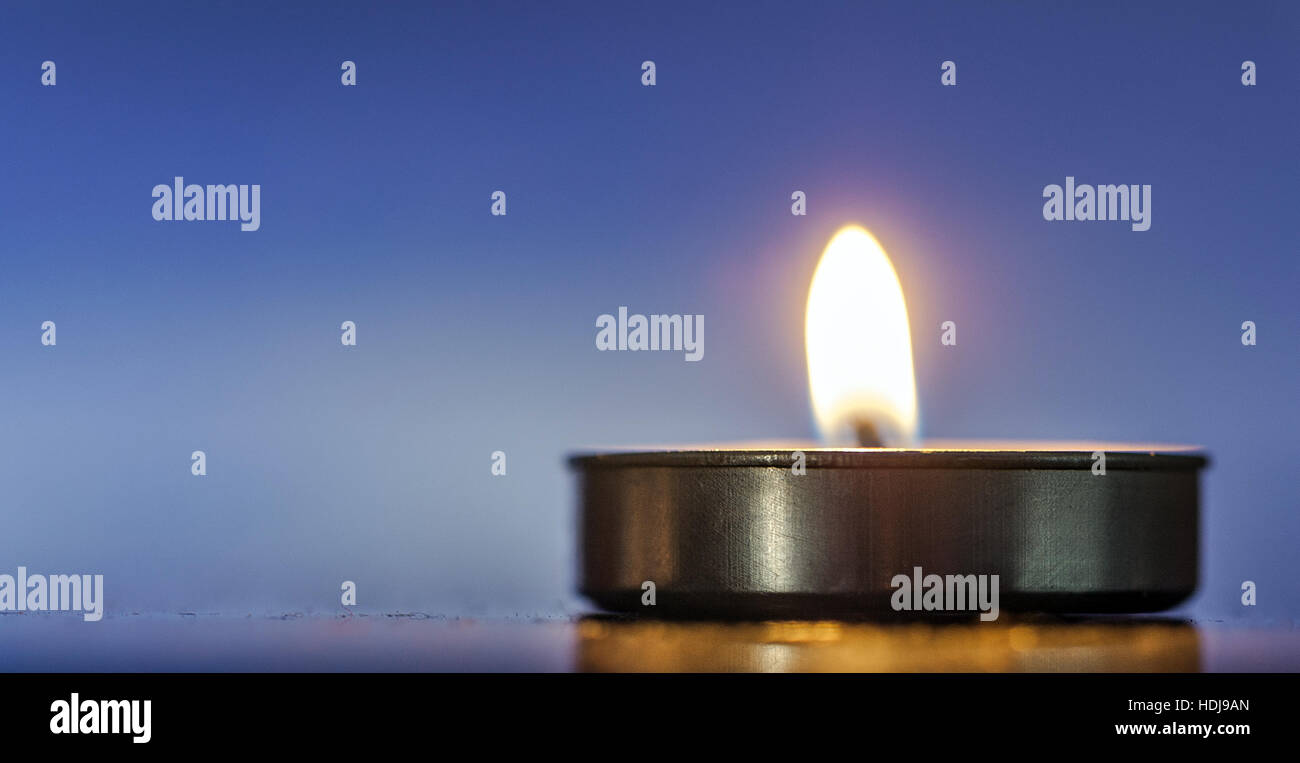 Scented Candle light over blue background Stock Photo - Alamy