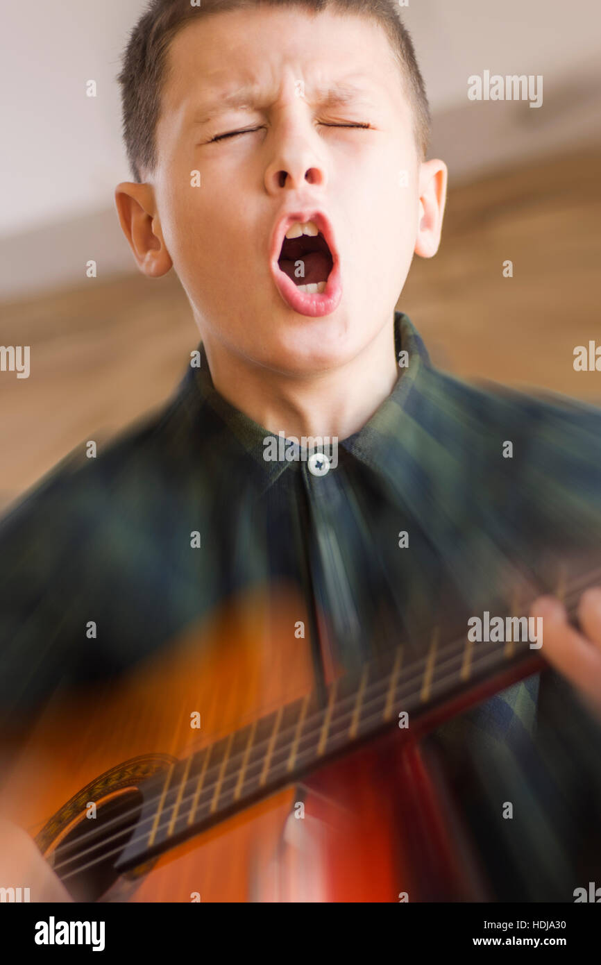 Young Boy Singing Out Loud While Playing Acoustic Guitar in Living Room ...