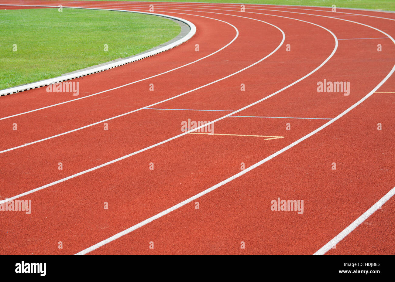 Red running tracks with green grassand white lines Stock Photo - Alamy