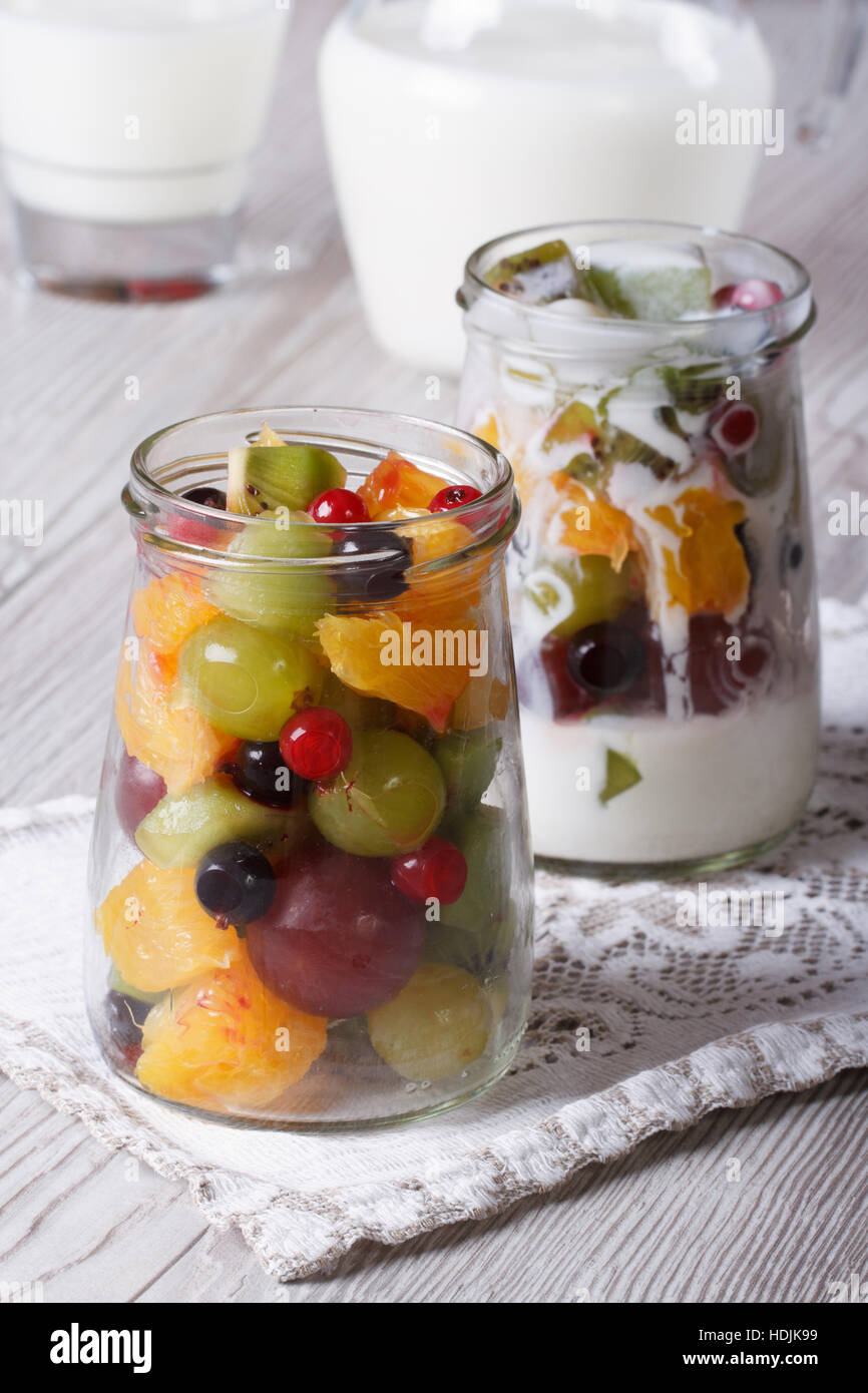 Fresh fruit in a glass jar and yoghurt close-up on the table vertical ...