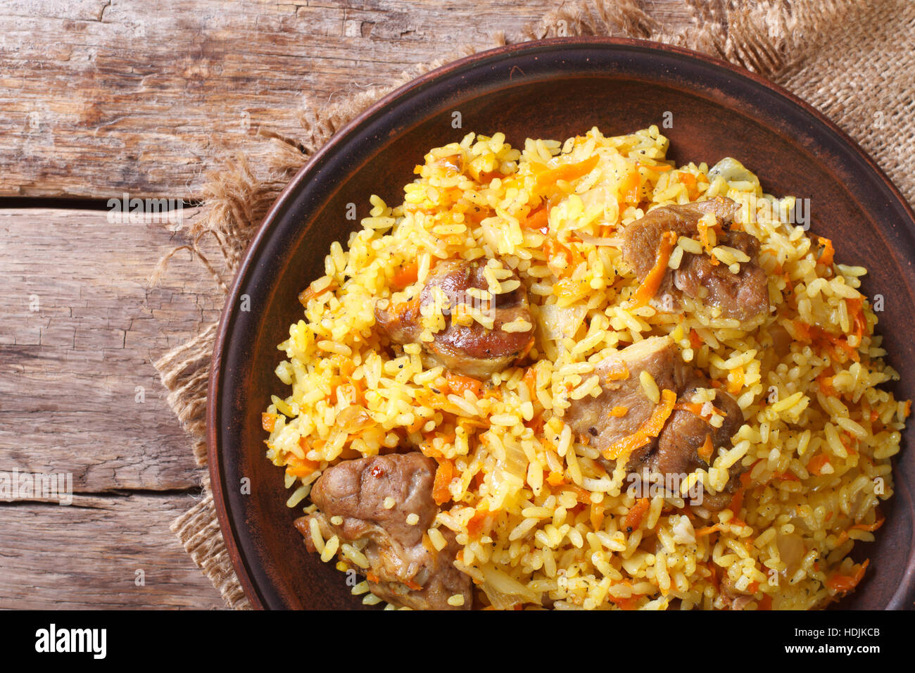 Rice with meat and vegetables on a brown plate closeup. horizontal view ...