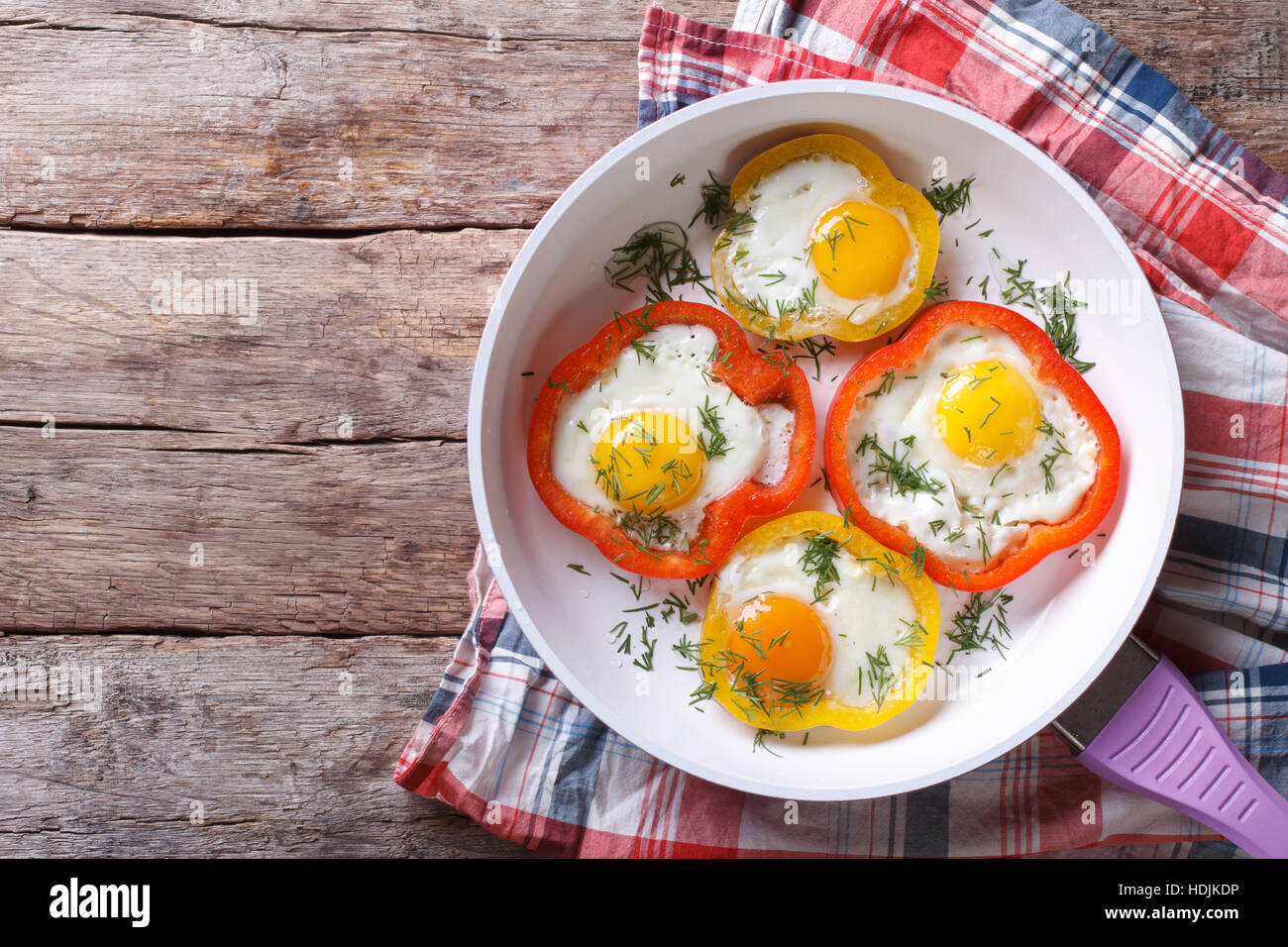 fried eggs in yellow and red peppers in a pan. horizontal view from ...