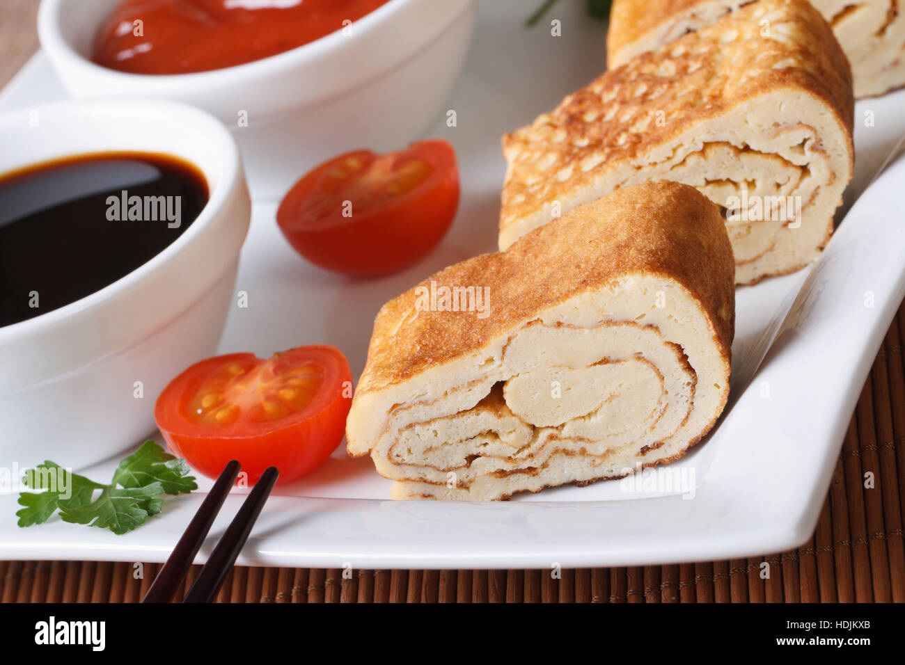 Japanese tamago egg with sauce and vegetables on a plate close-up ...